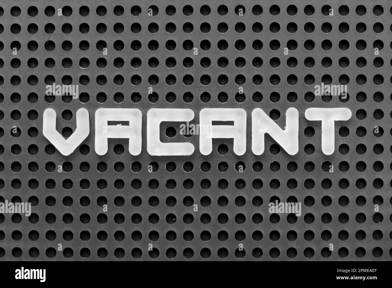 White alphabet letter in word vacant on black pegboard background Stock ...