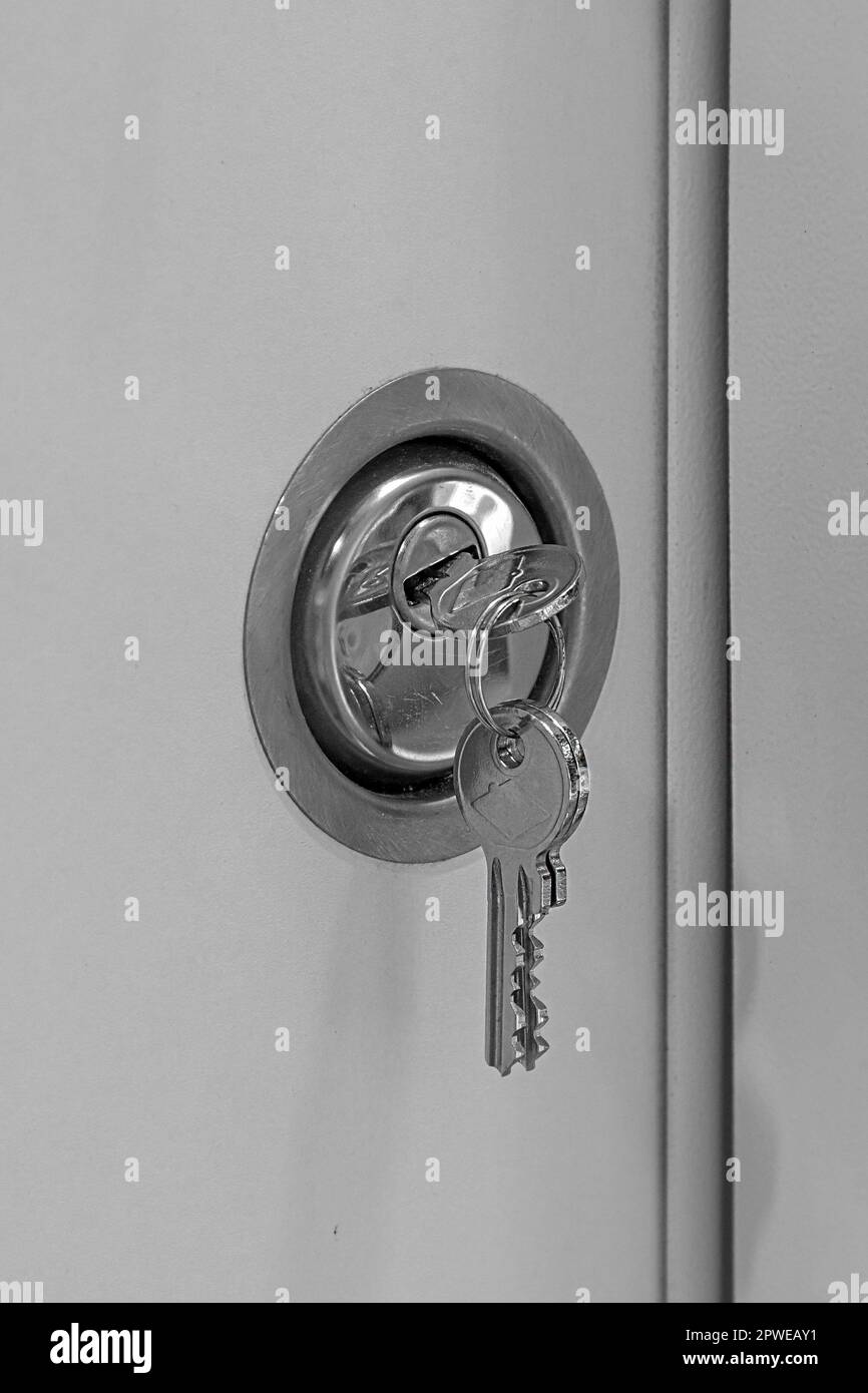 Keys hanging in a door keyhole on the wall Stock Photo - Alamy