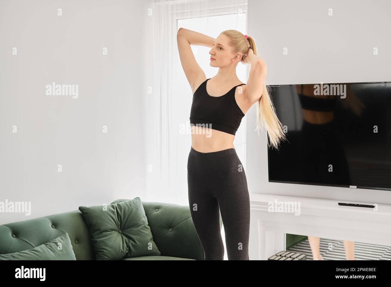 Active blonde woman does twisting exercises in bright apartment Stock ...
