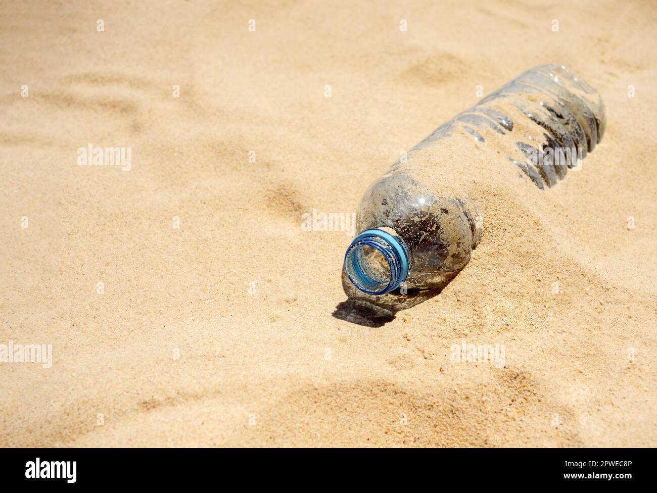 Plastic bottle on sandy beach. Empty uncapped used plastic drinking ...