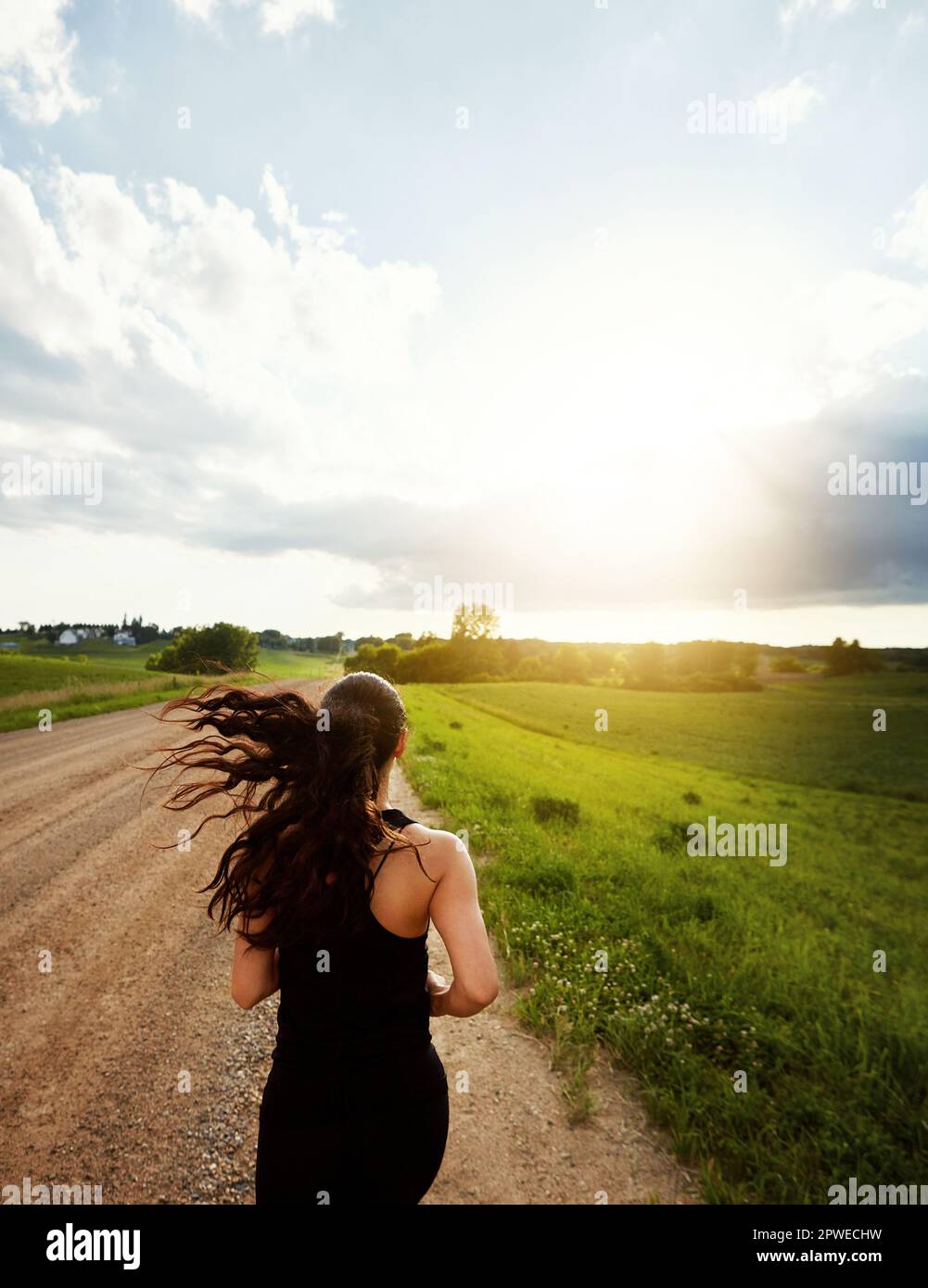 Chasing the horizon. Rearview shot of a young woman out for a run on a beautiful day Stock Photo ...