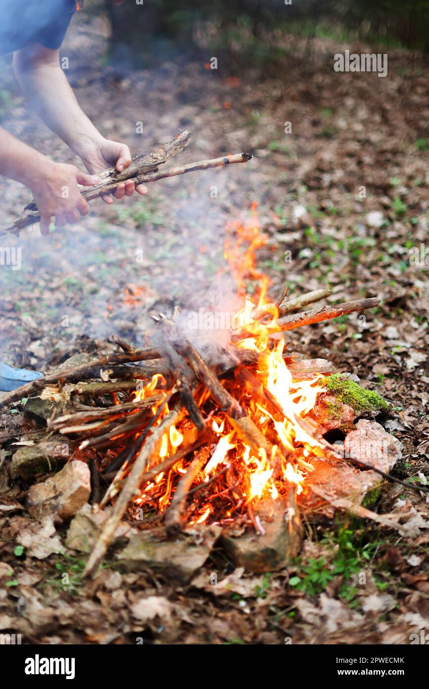 Low angle shot of a man is trying make a fire in the forest. Close-up ...