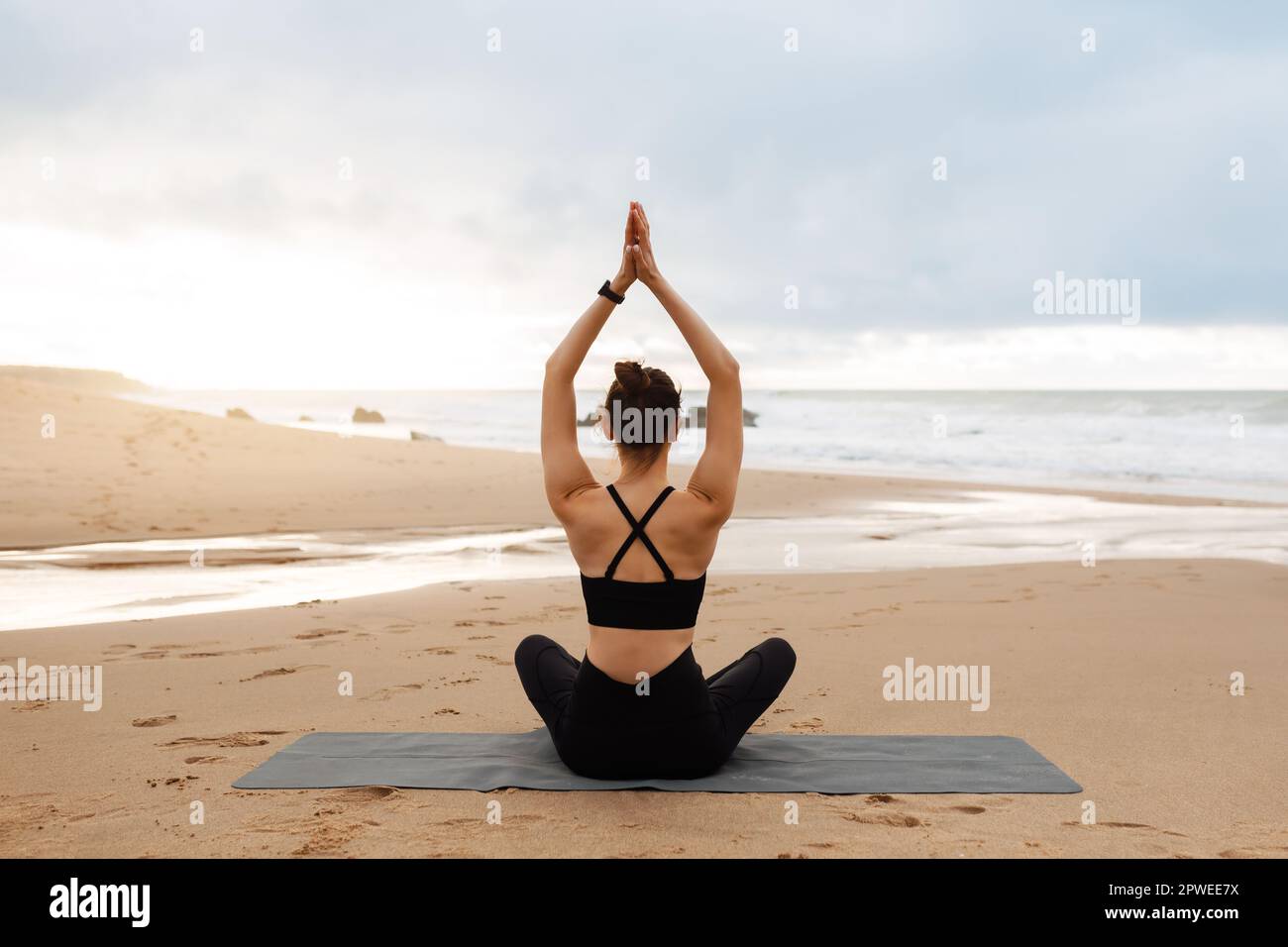 Outdoor yoga. Woman meditating with hands clasped above head ...