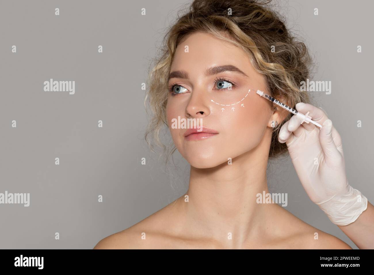 Beautician doctor making injection to woman with drawn line under eye ...