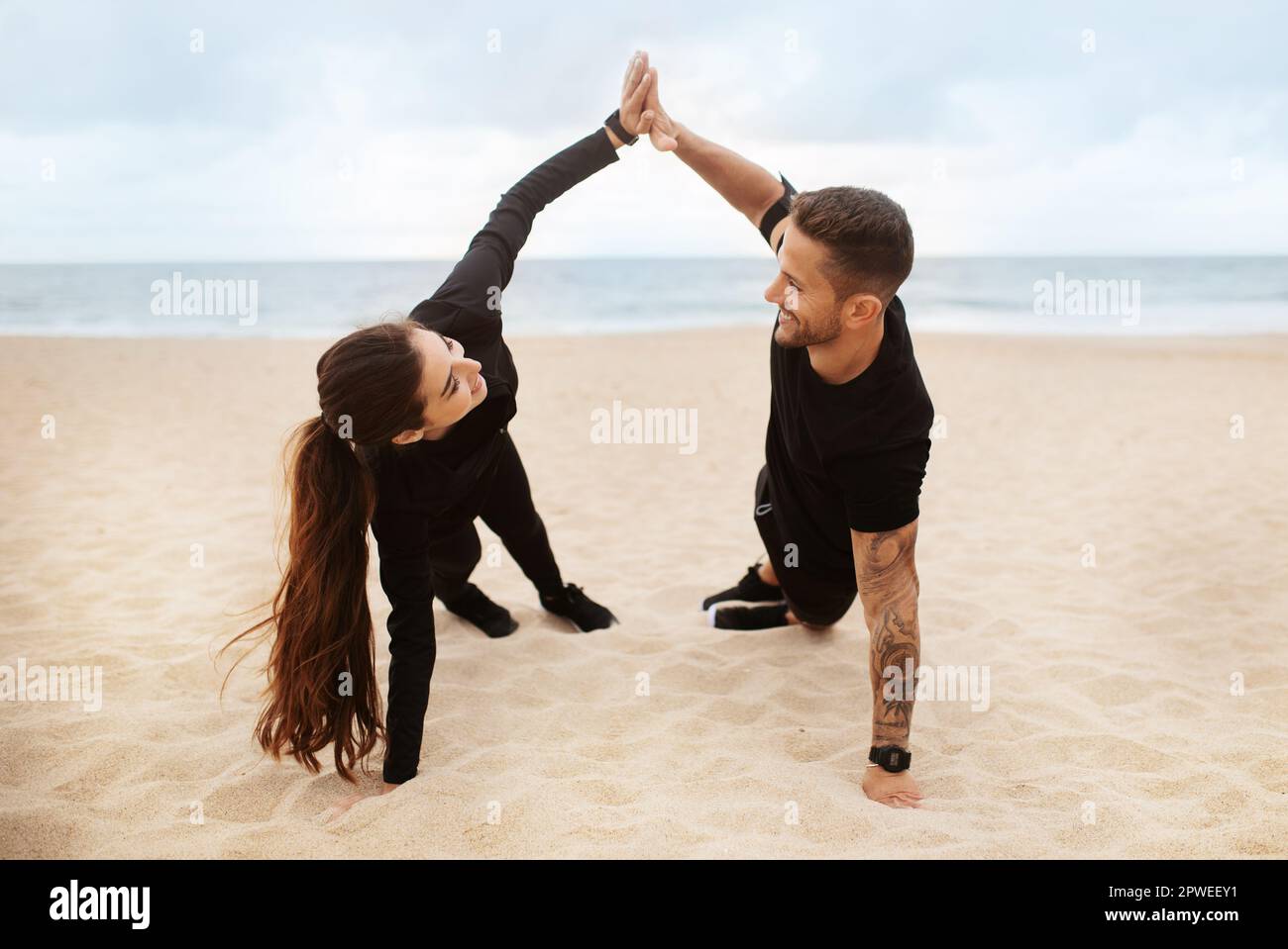 Happy couple in sportswear standing in side plank and giving high five ...