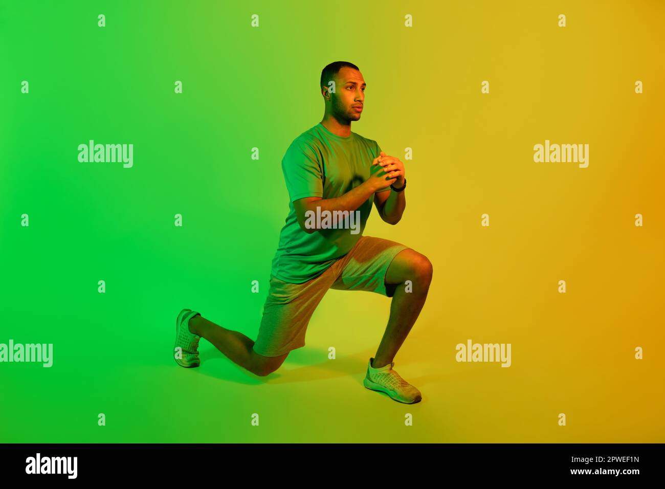African Fitness Guy Doing Lunge Exercising In Green Neon Light Stock ...