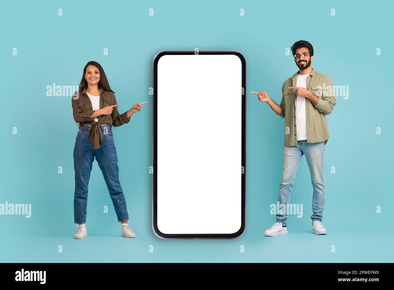 Happy indian couple pointing at big cell phone, mockup Stock Photo - Alamy