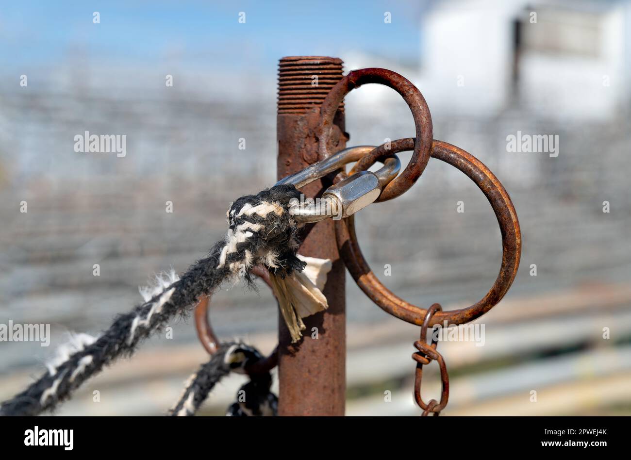 Weathered rope with clevis attached to a rusty steel pipe hitching post ...