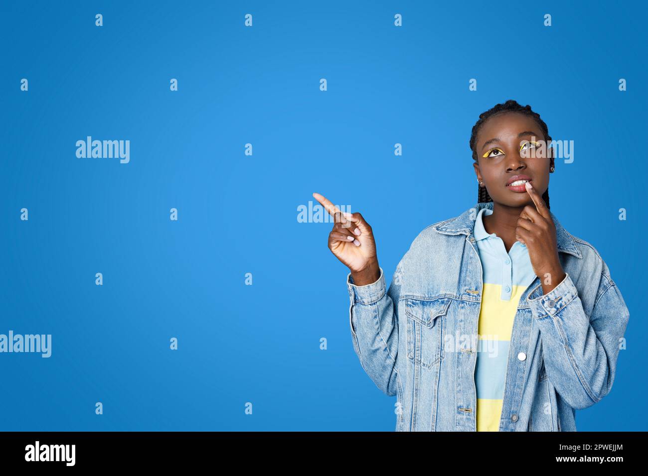 Pensive young black woman touching lip and pointing copy space Stock ...