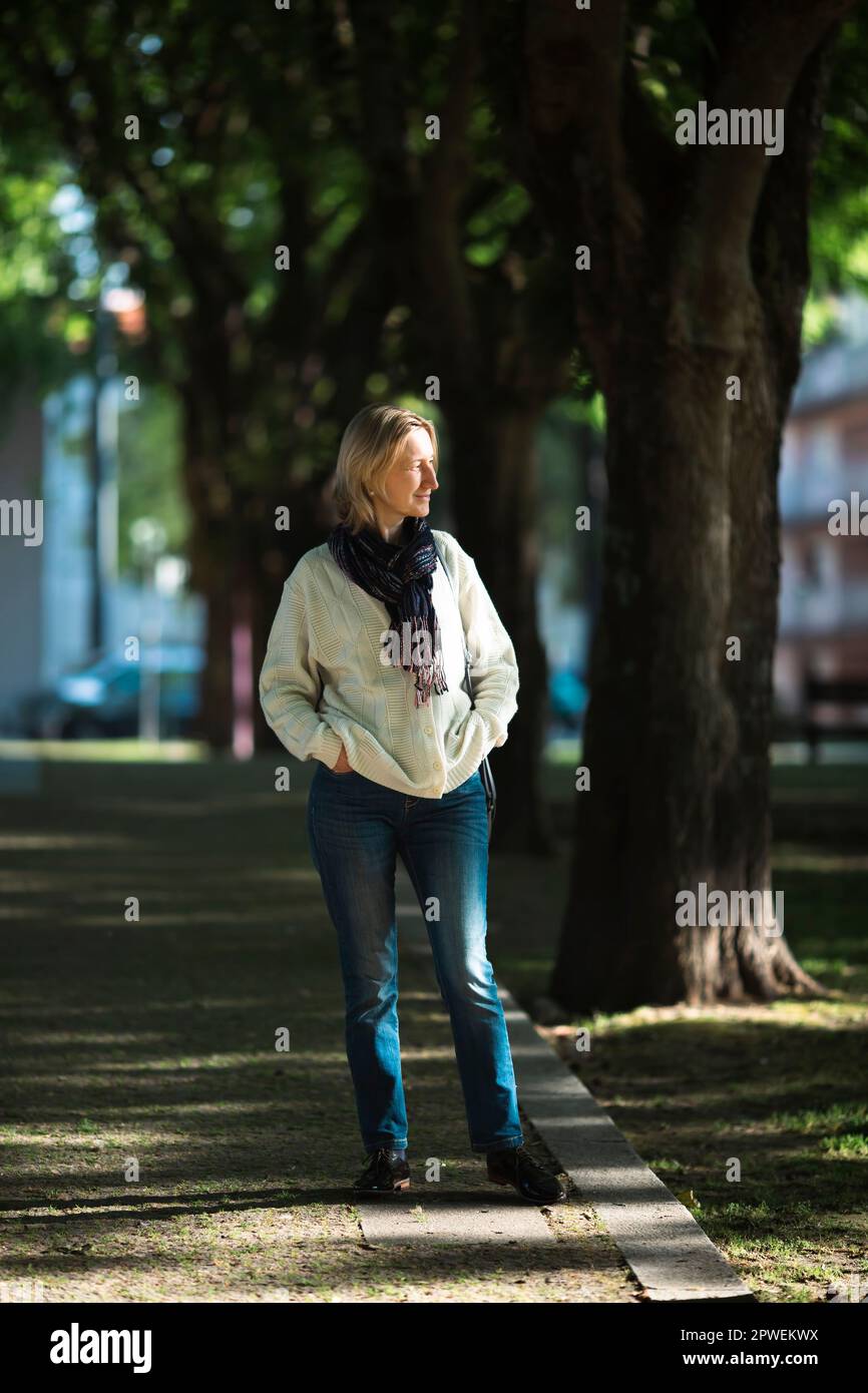 A woman is standing in a shady green alley Stock Photo - Alamy