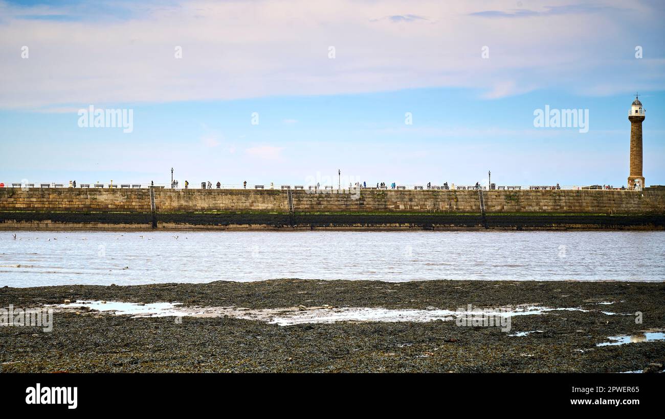 Tourists walking along Whitby harbour wall on a spring day Stock Photo ...