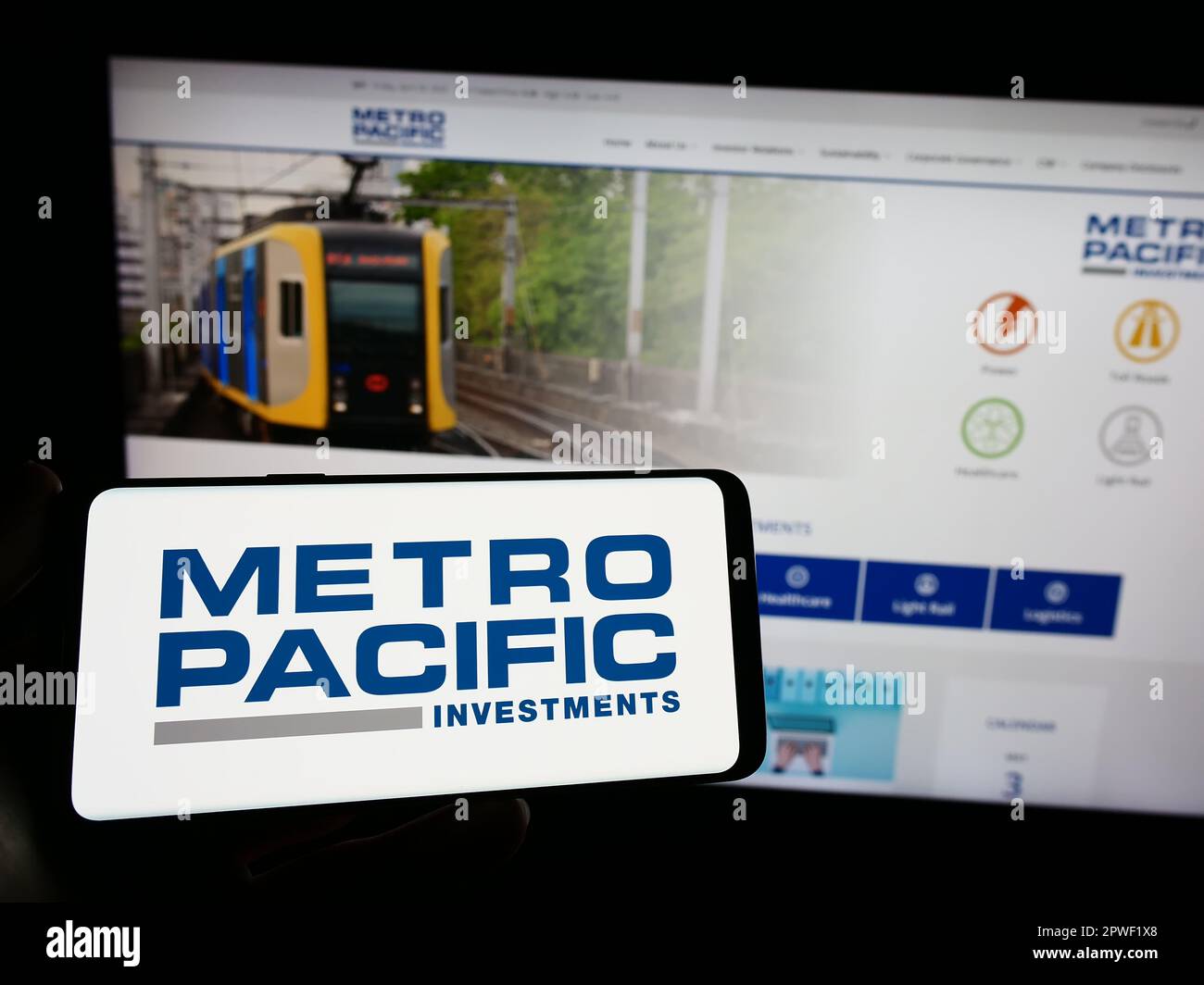 Person holding smartphone with logo of Metro Pacific Investments ...