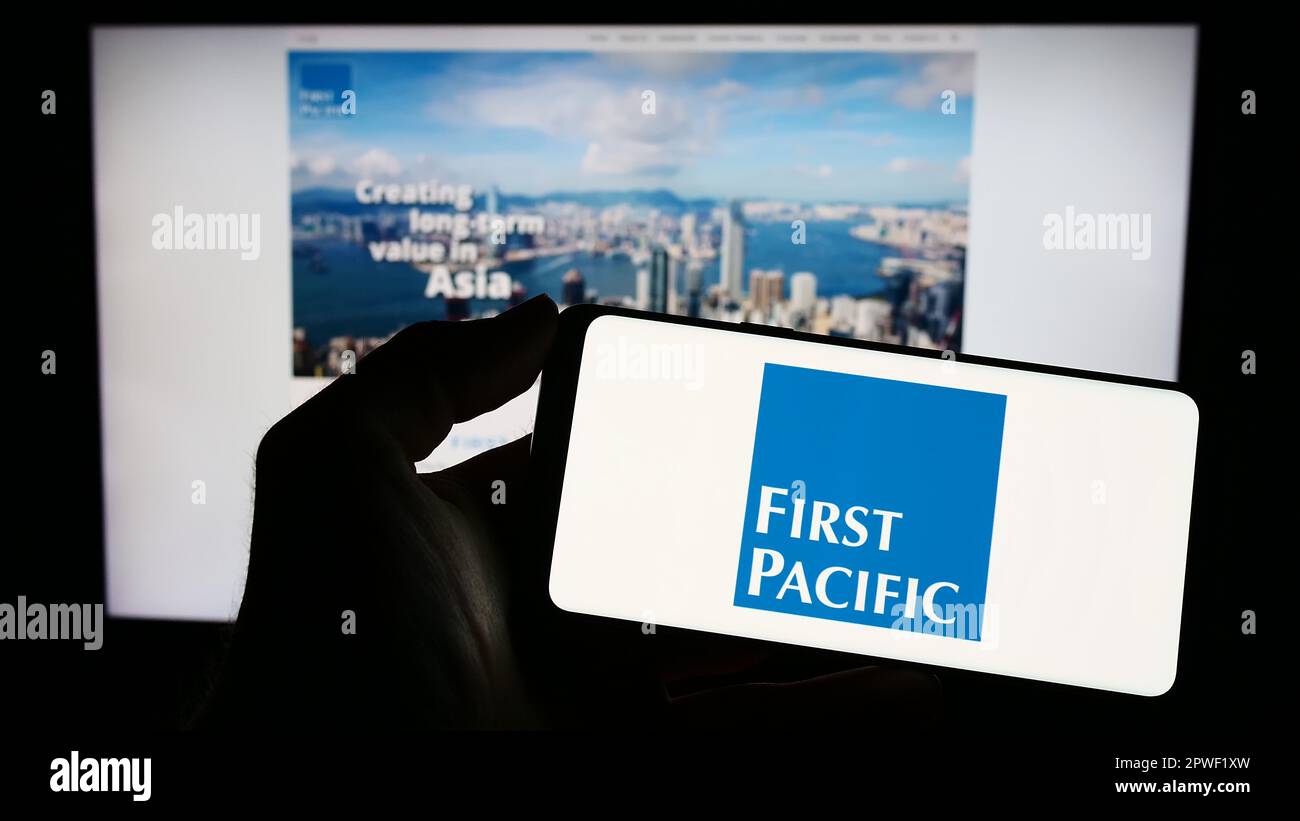 Person holding smartphone with logo of investment firm First Pacific ...