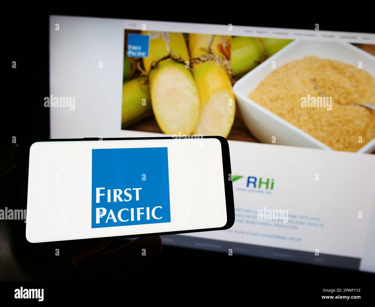 Person holding mobile phone with logo of investment firm First Pacific ...