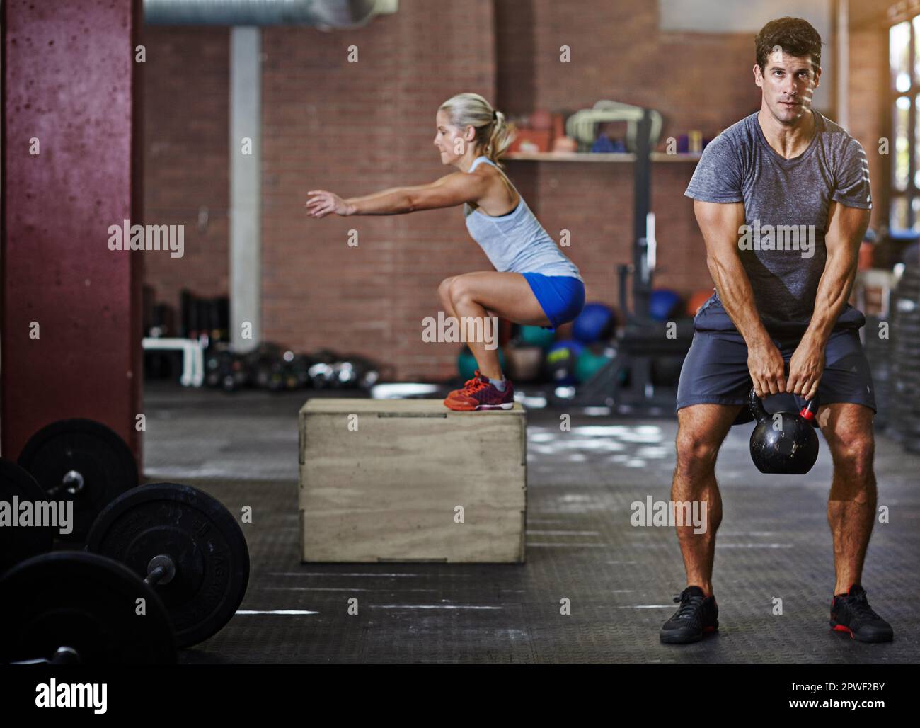 Make your workout count. two people working out with kettlebells in a ...