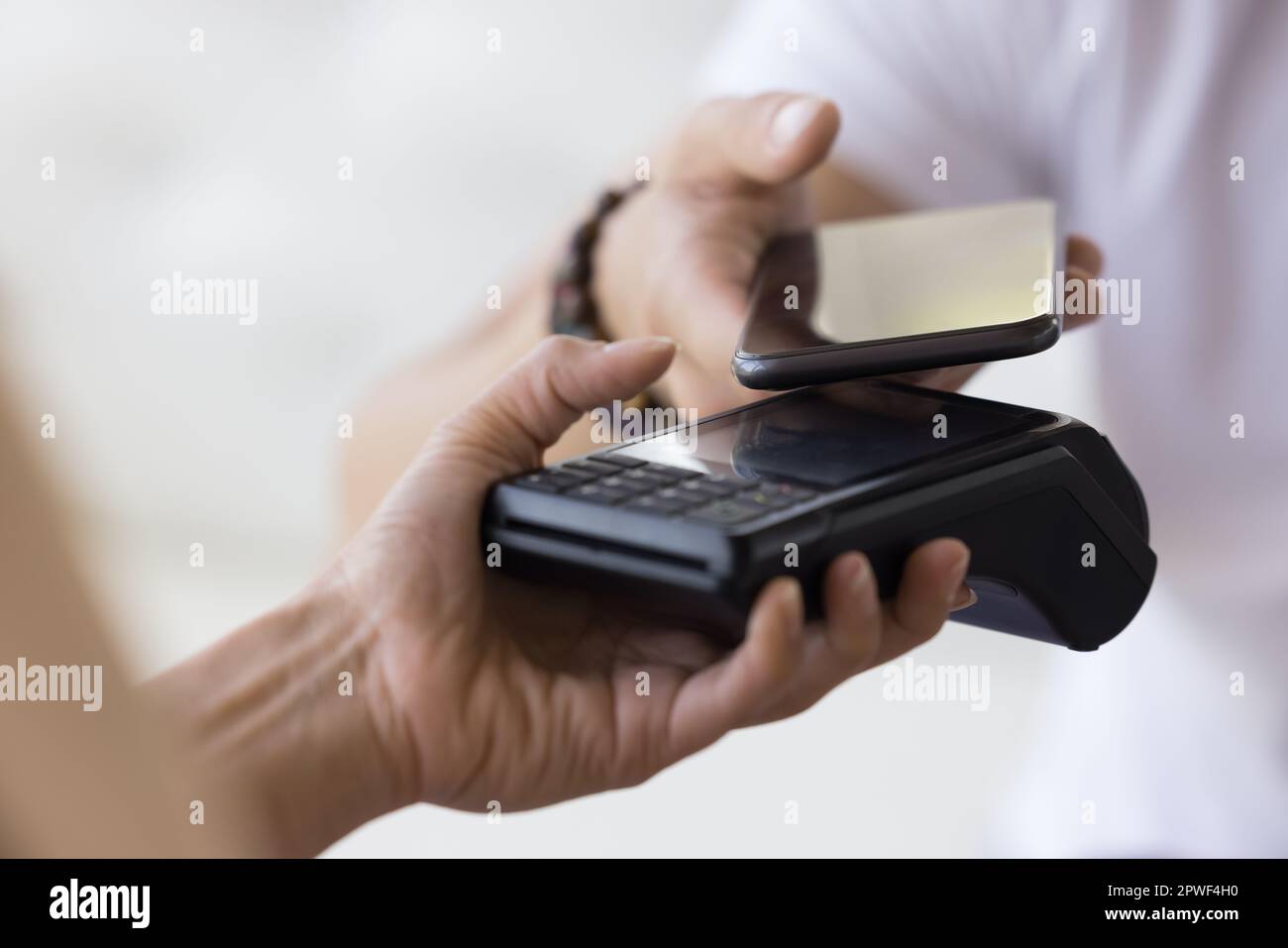 Man holding smartphone paying bills using portable payment terminal ...