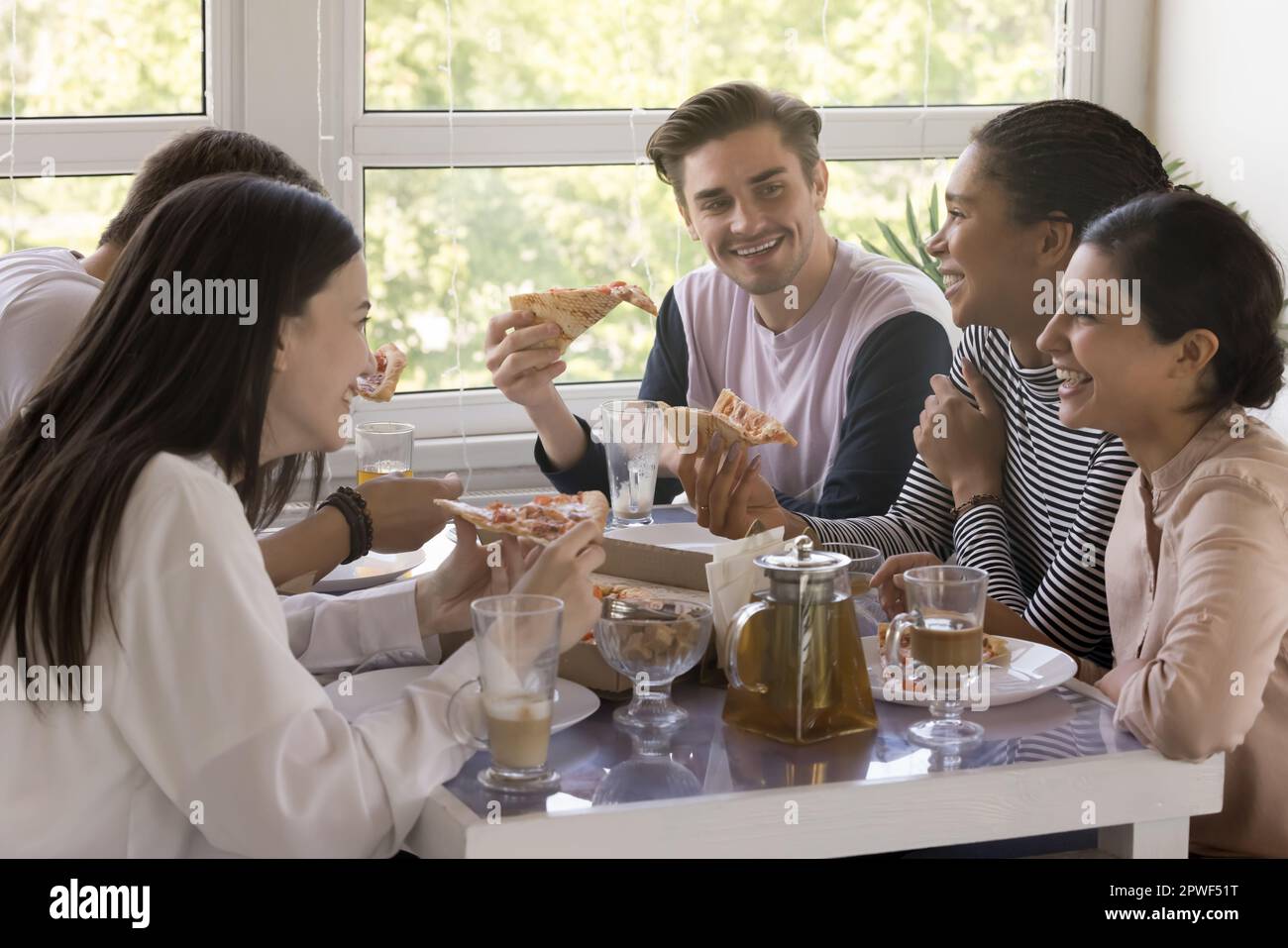 Group of happy millennial people enjoy talk and eating pizza Stock ...