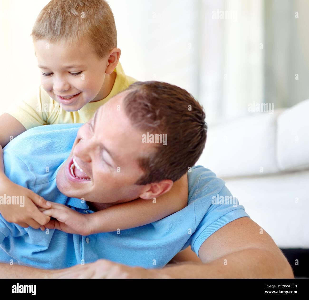 Giving dad a play fight. Young son playfully wrestling with his dad in ...