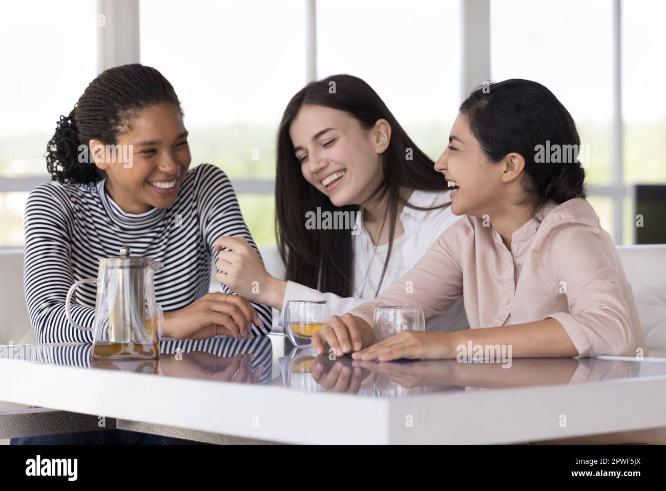 Group of multiracial girls enjoy talk, laughing seated at table Stock ...