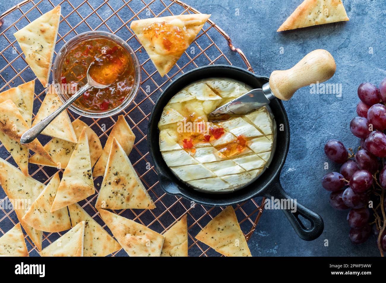 Baked brie cheese in a cast iron pan with pita triangles and red pepper ...