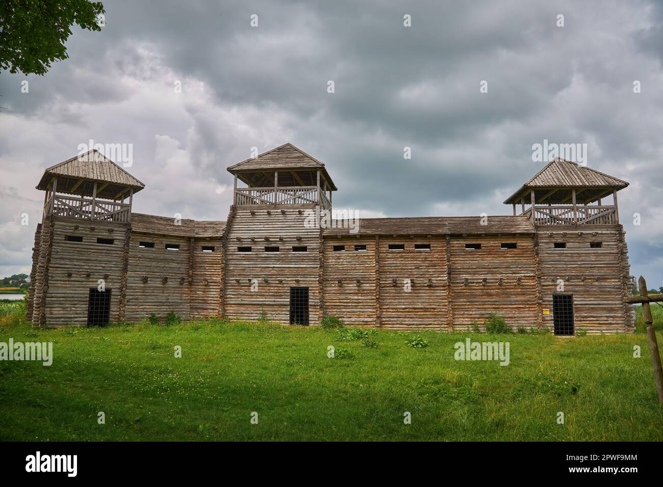 An old wooden fortress surrounded by a fence with sharp peaks on a ...