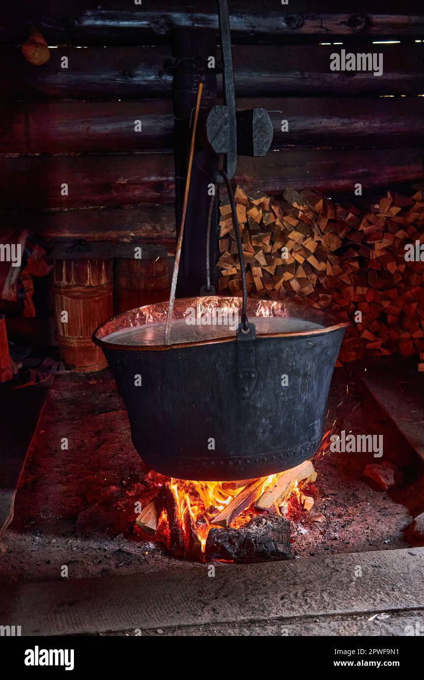 A large vat in which cheese is cooked over an open fire. The black ...