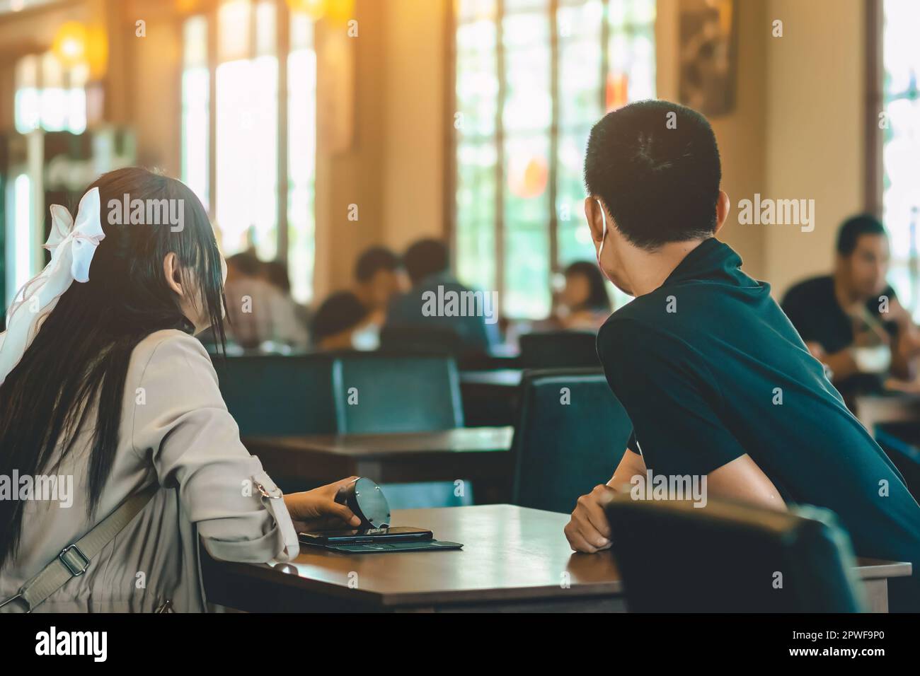 Back view of Asian woman with backpack holding wireless queue caller ...