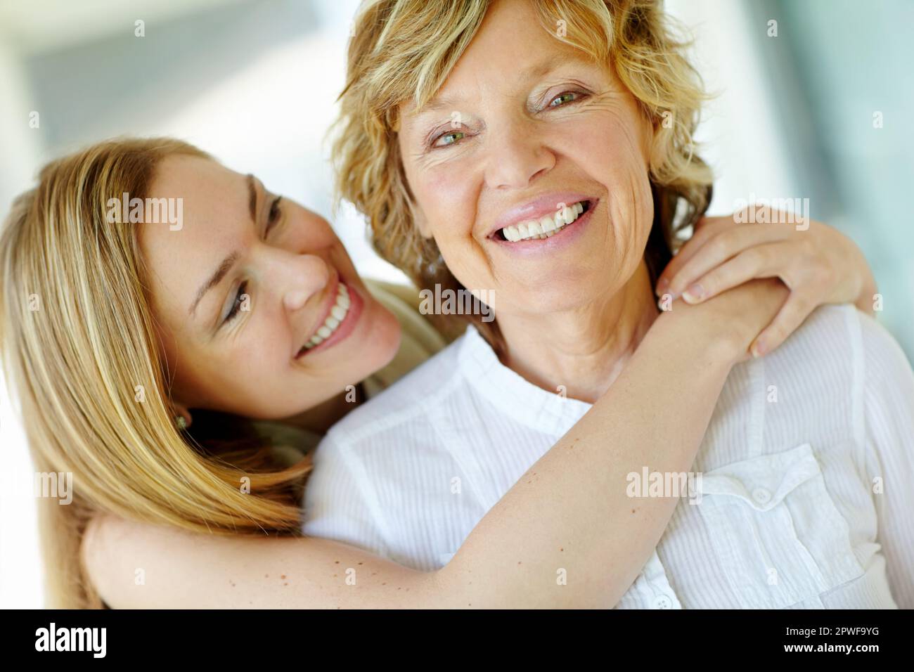 Giving her a great big hug. A smiling senior woman receiving a hug from ...