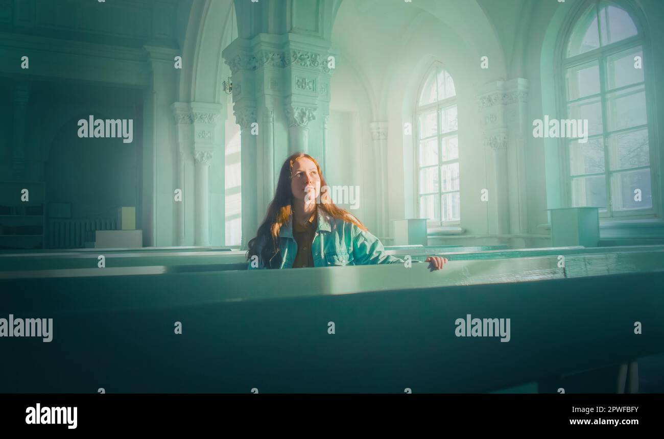 A beautiful ginger young woman is sitting on simple benches in a ...