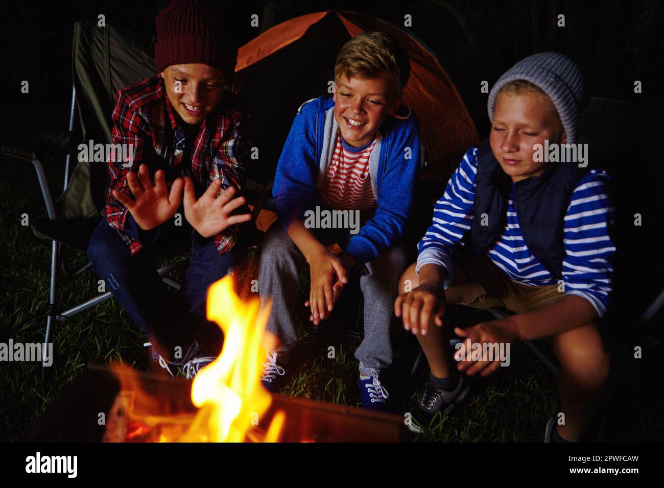 Tales around the campfire. three young boys sitting by the campfire ...