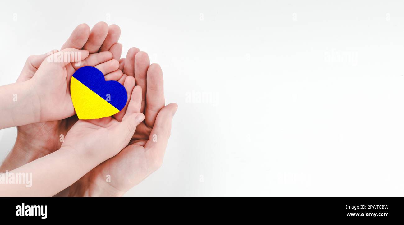 The hands of father and son hold the flag of Ukraine in the shape of a ...