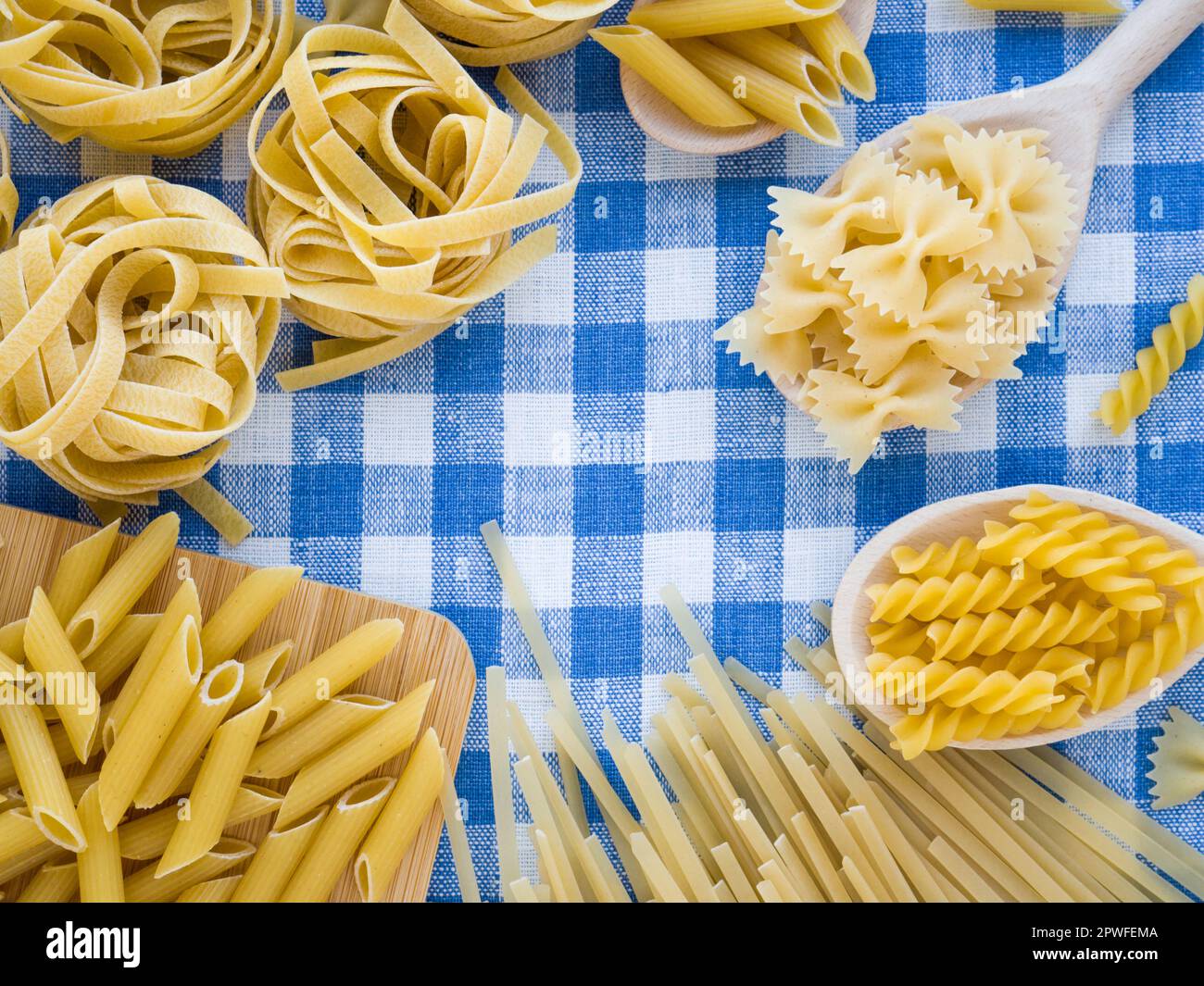 Mixed dried pasta selection on blue and white linen towel as background ...
