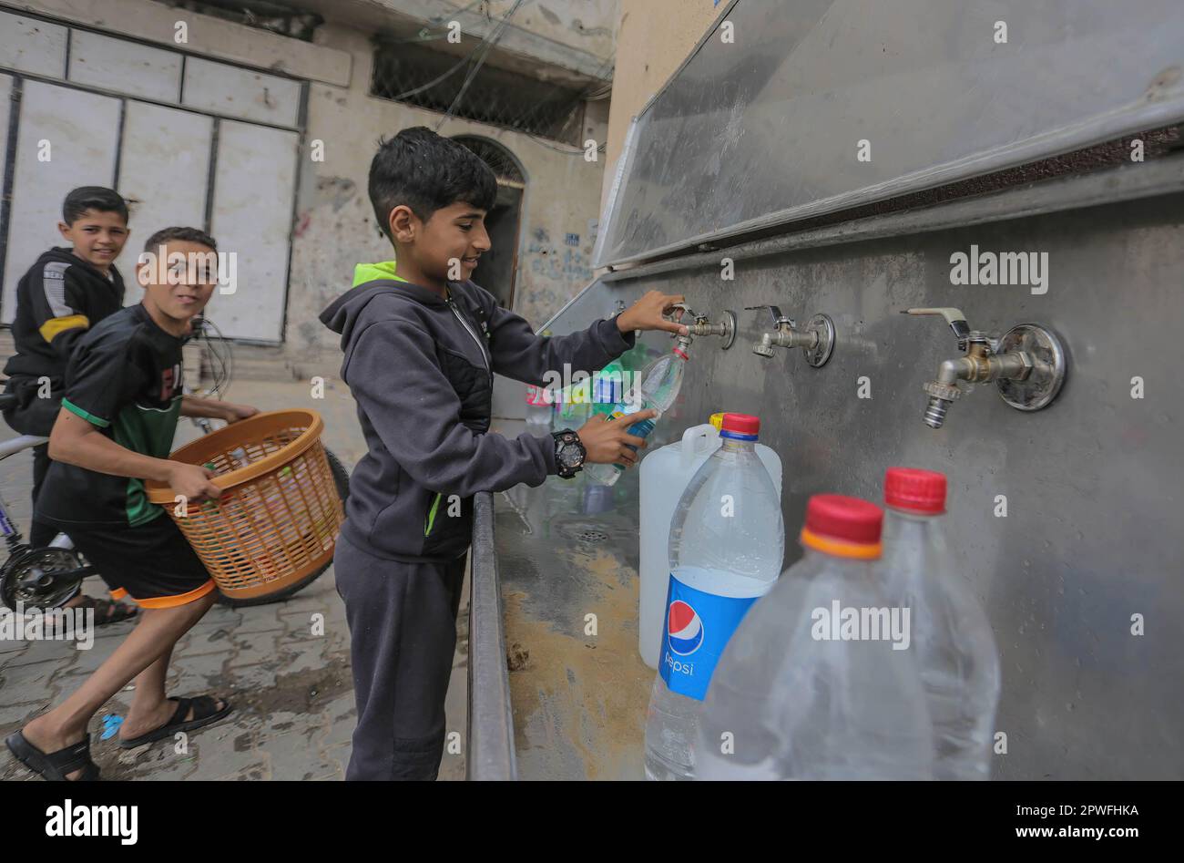Gaza, Palestine. 28th Apr, 2023. A Palestinian boy fills a water bottle at a tap in the town of ...