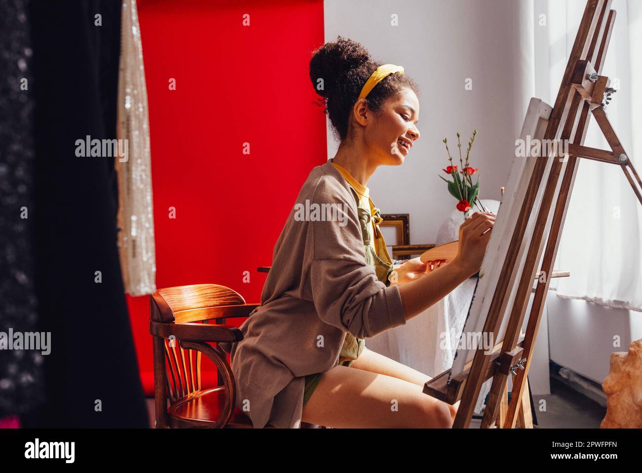 Young female creative pretty african american artist paints picture with oil paints in art ...