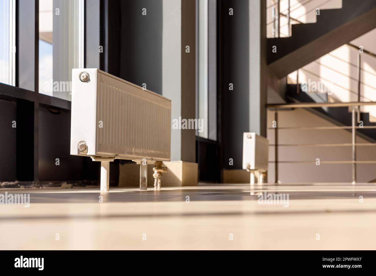 Vertically installed central heating radiator on the floor at the fully ...