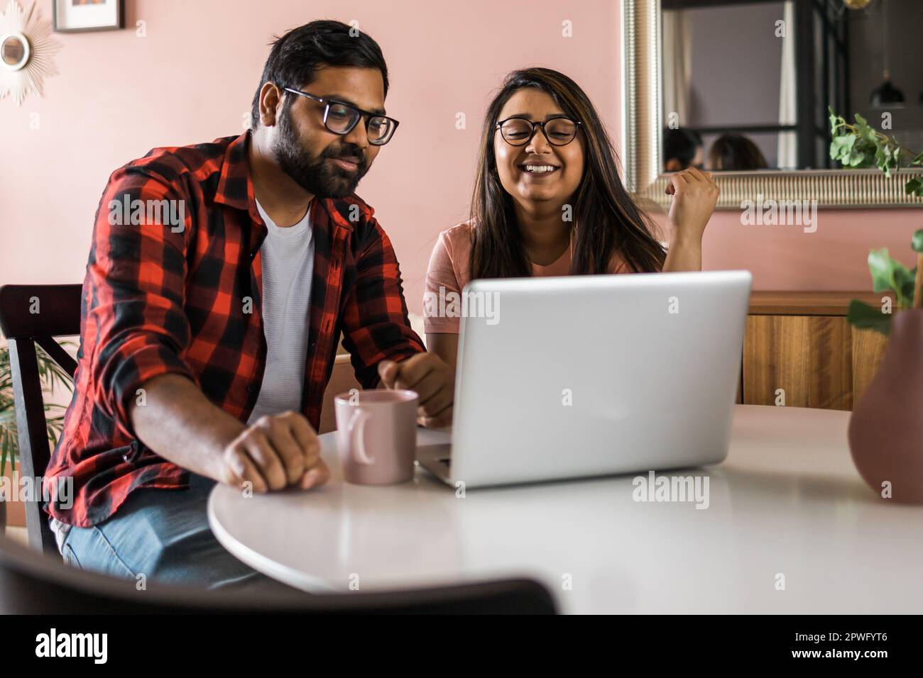 Happy indian family couple cuddle at desk make video call to friends ...