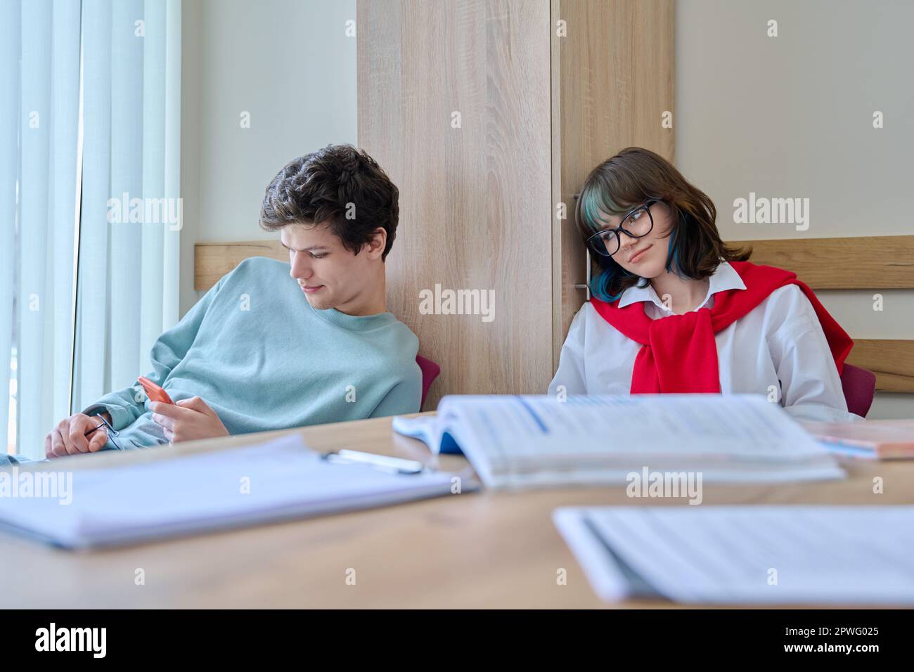 Teenage students sitting on break in classroom, resting using ...