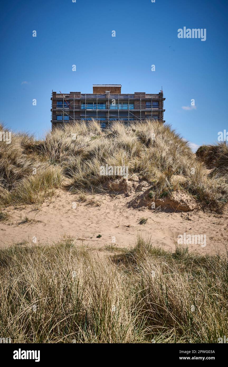 Scaffold covered building behind sand dunes on St Annes beach Stock ...