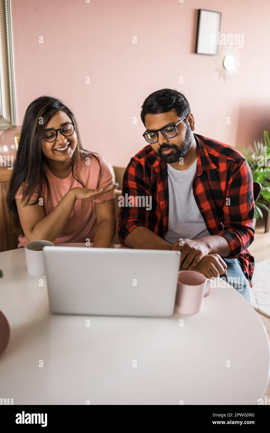 Happy indian family couple cuddle at desk make video call to friends ...