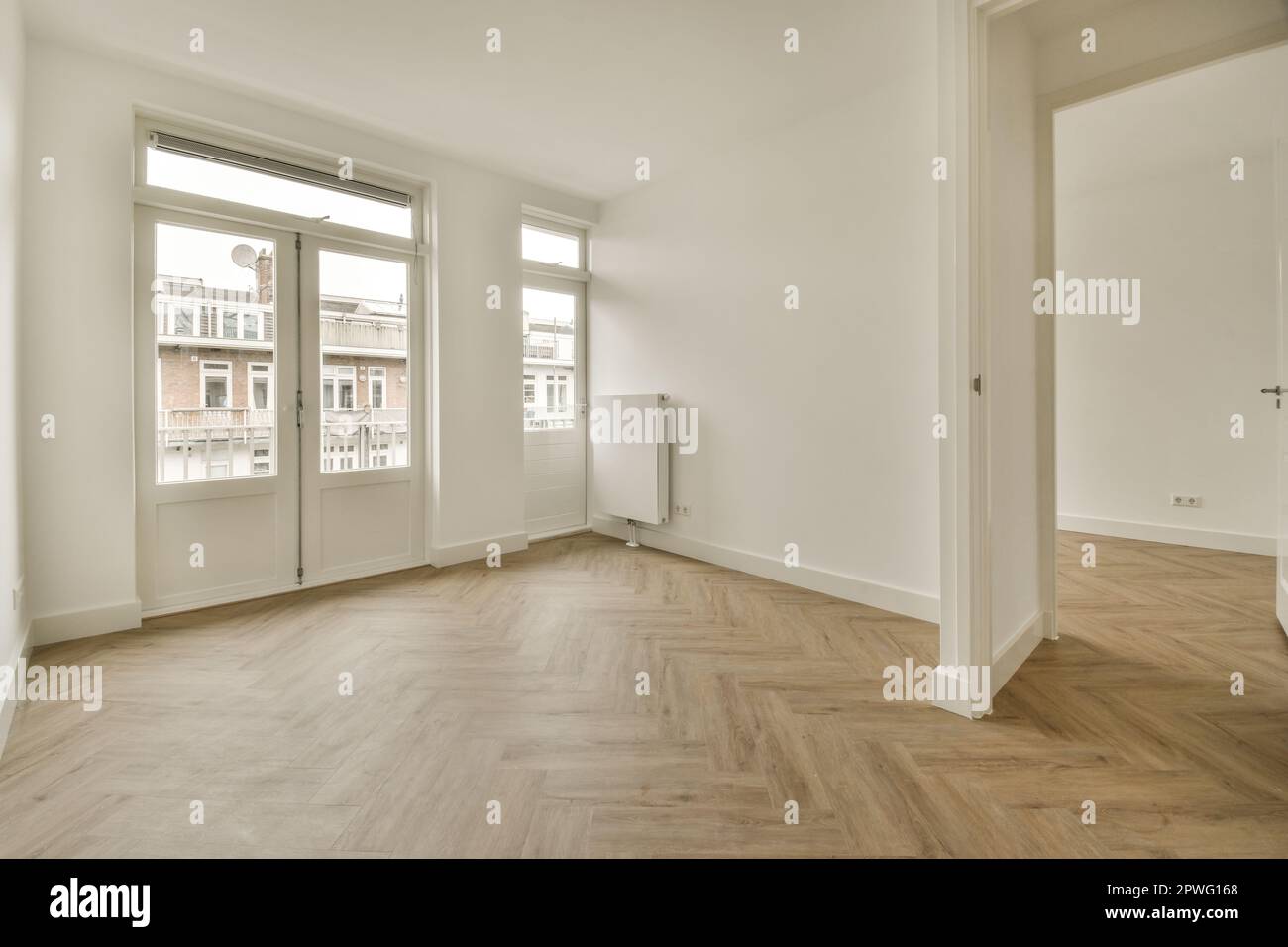 an empty room with wood flooring and white walls, there is a door ...