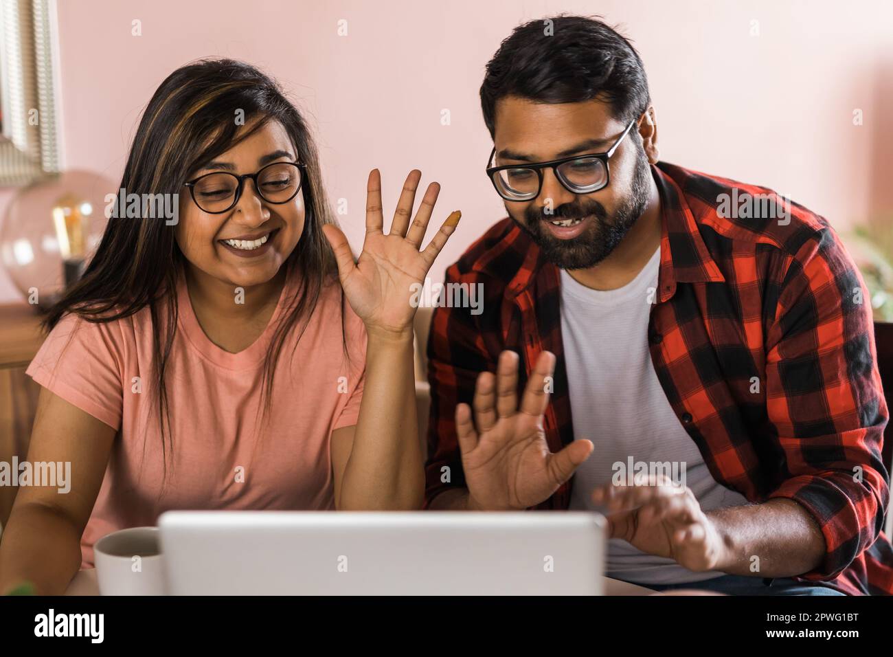 Happy indian family couple cuddle at desk make video call to friends ...