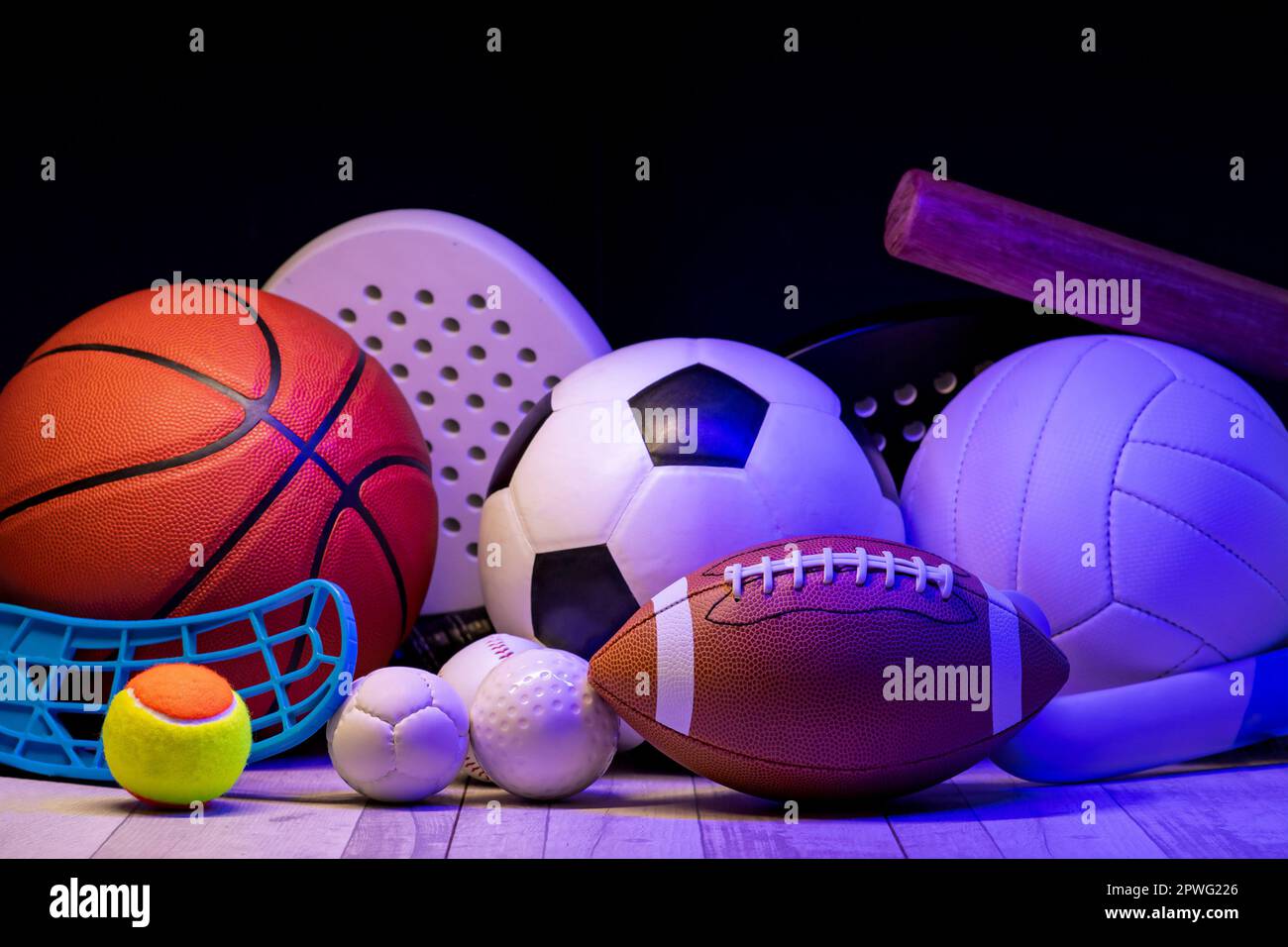 Sports equipment, rackets and balls on hardwood court floor with neon ...