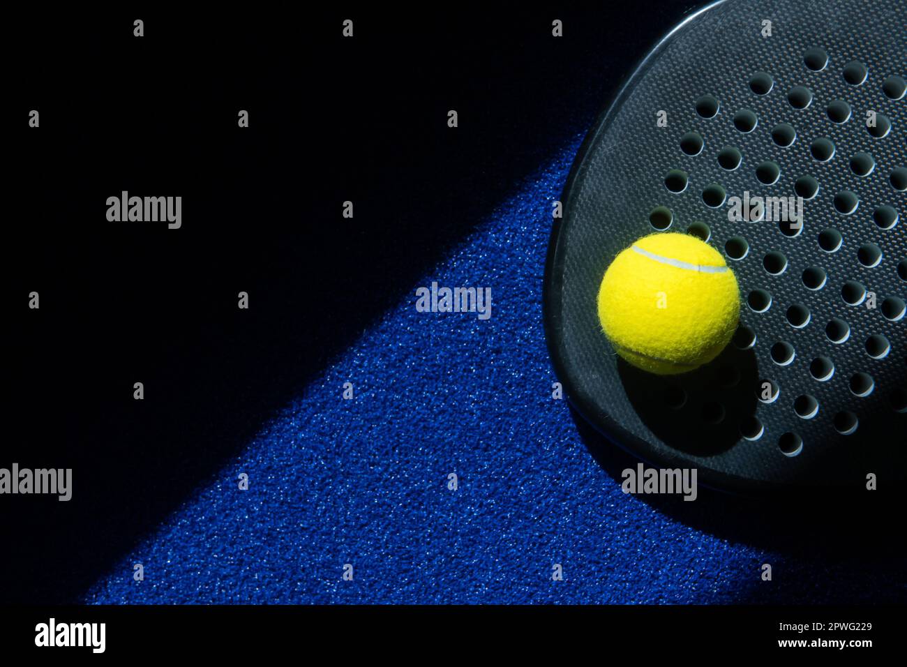 Black professional paddle tennis racket and ball with natural lighting ...