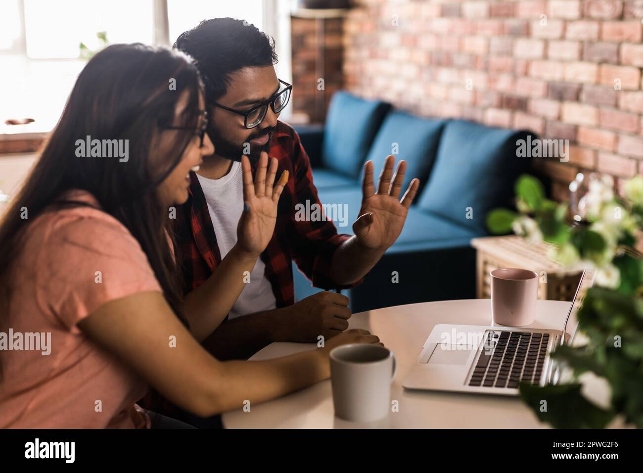 Happy indian family couple cuddle at desk make video call to friends ...