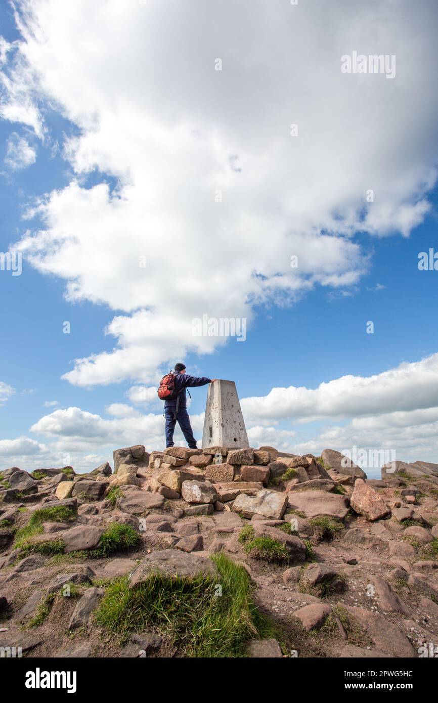 Man at the trig point hill walking in the Peak District National park ...