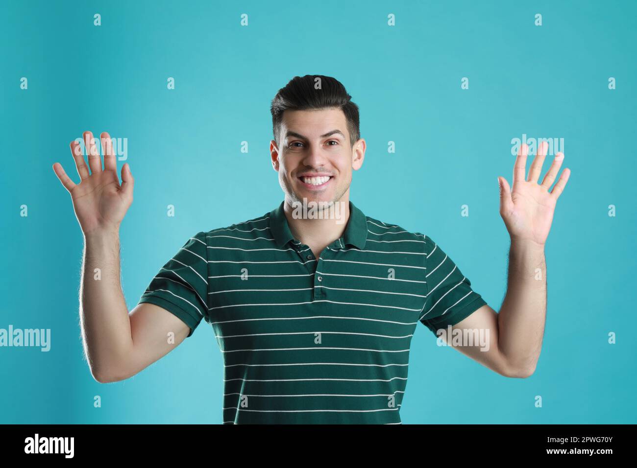 Cheerful man waving to say hello on turquoise background Stock Photo ...