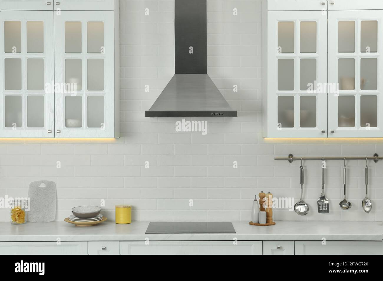 Elegant kitchen interior with modern range hood over cooktop and ...