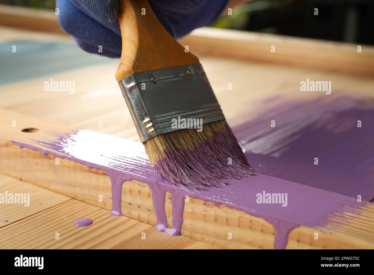 Worker applying violet paint onto wooden surface, closeup Stock Photo ...