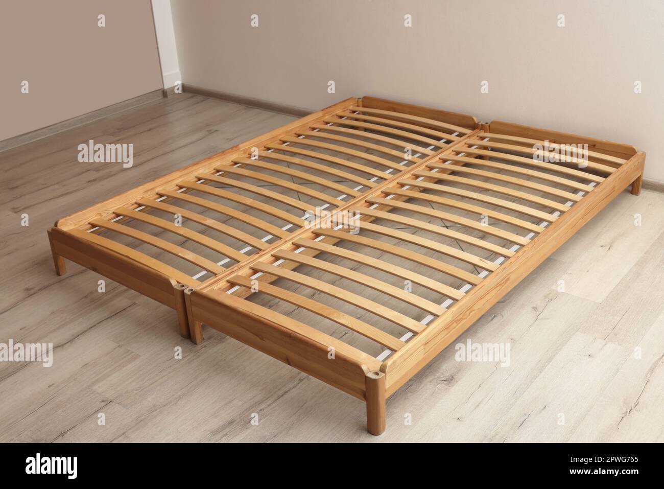 Wooden bed frame on floor in room Stock Photo - Alamy