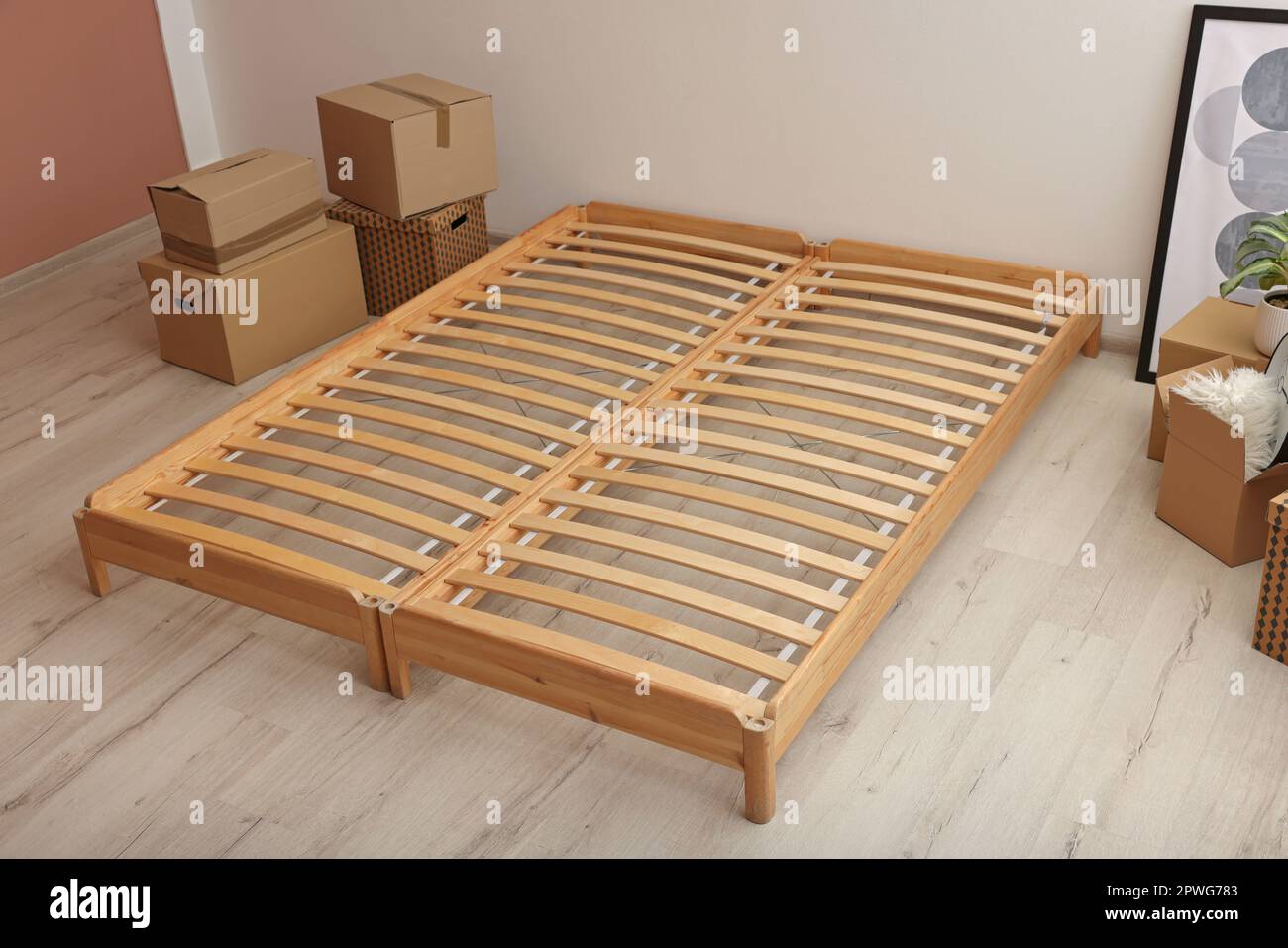 Wooden bed frame and cardboard boxes on floor in room Stock Photo - Alamy